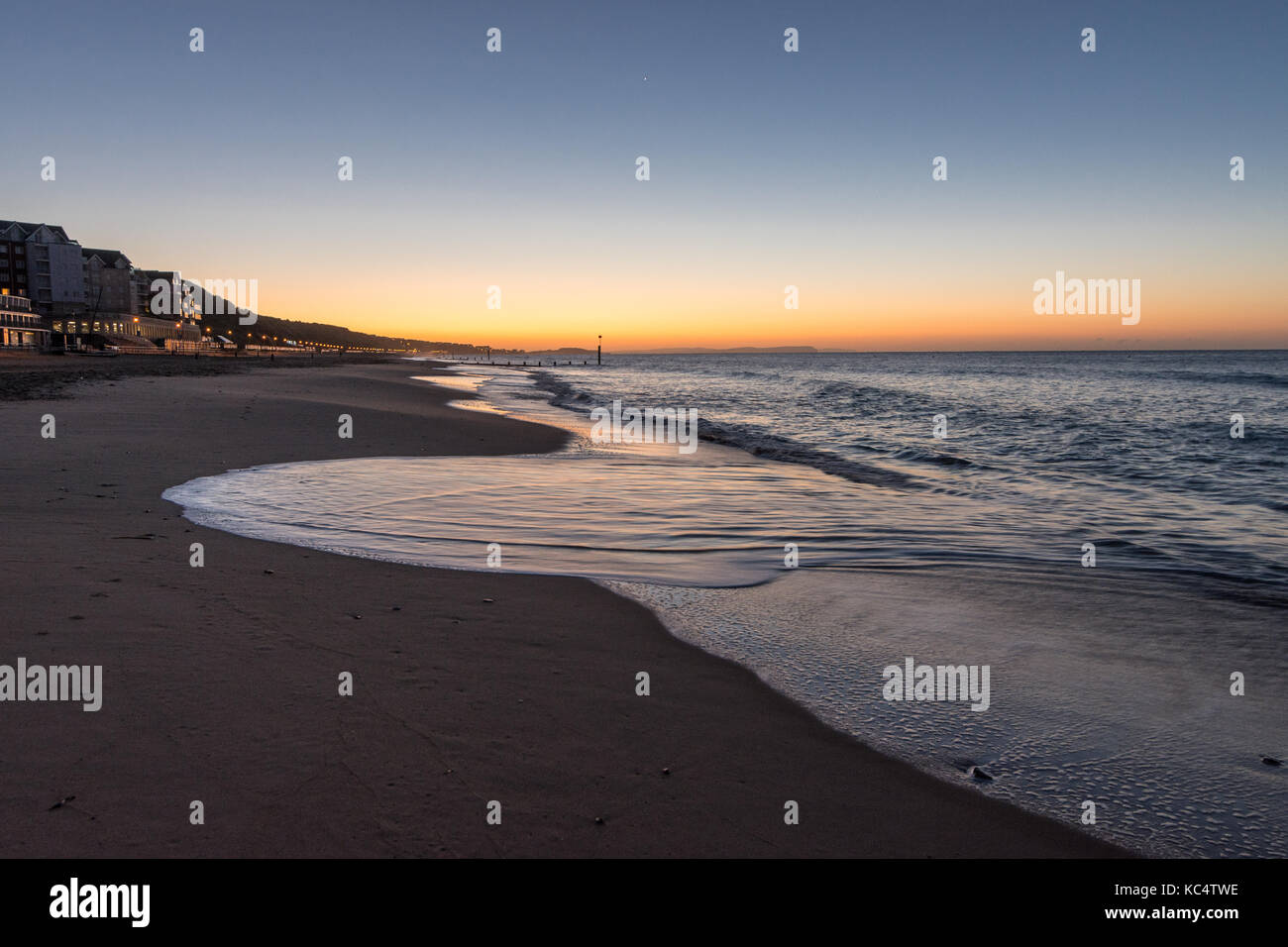 Cloudless skies above the beach as the morning sunlight edges above the ...