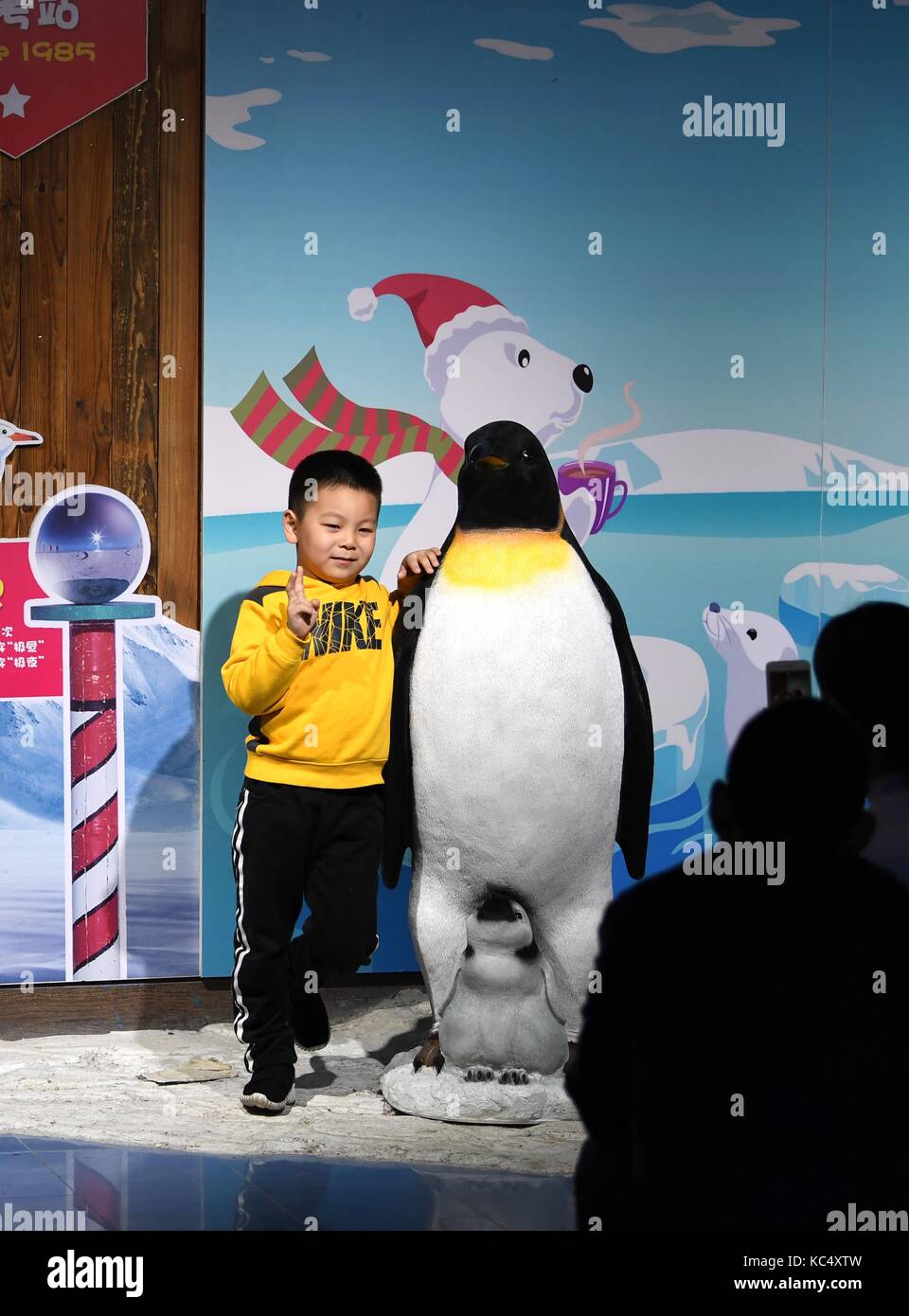 Hefei. 3rd Oct, 2017. A boy poses with a model of a penguin at Hefei ...