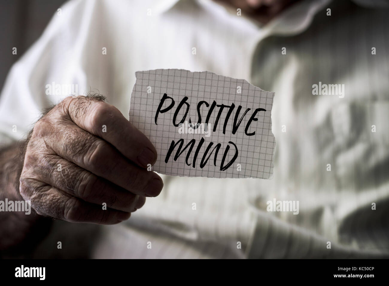 closeup of an old caucasian man with a note in his hands with the text ...