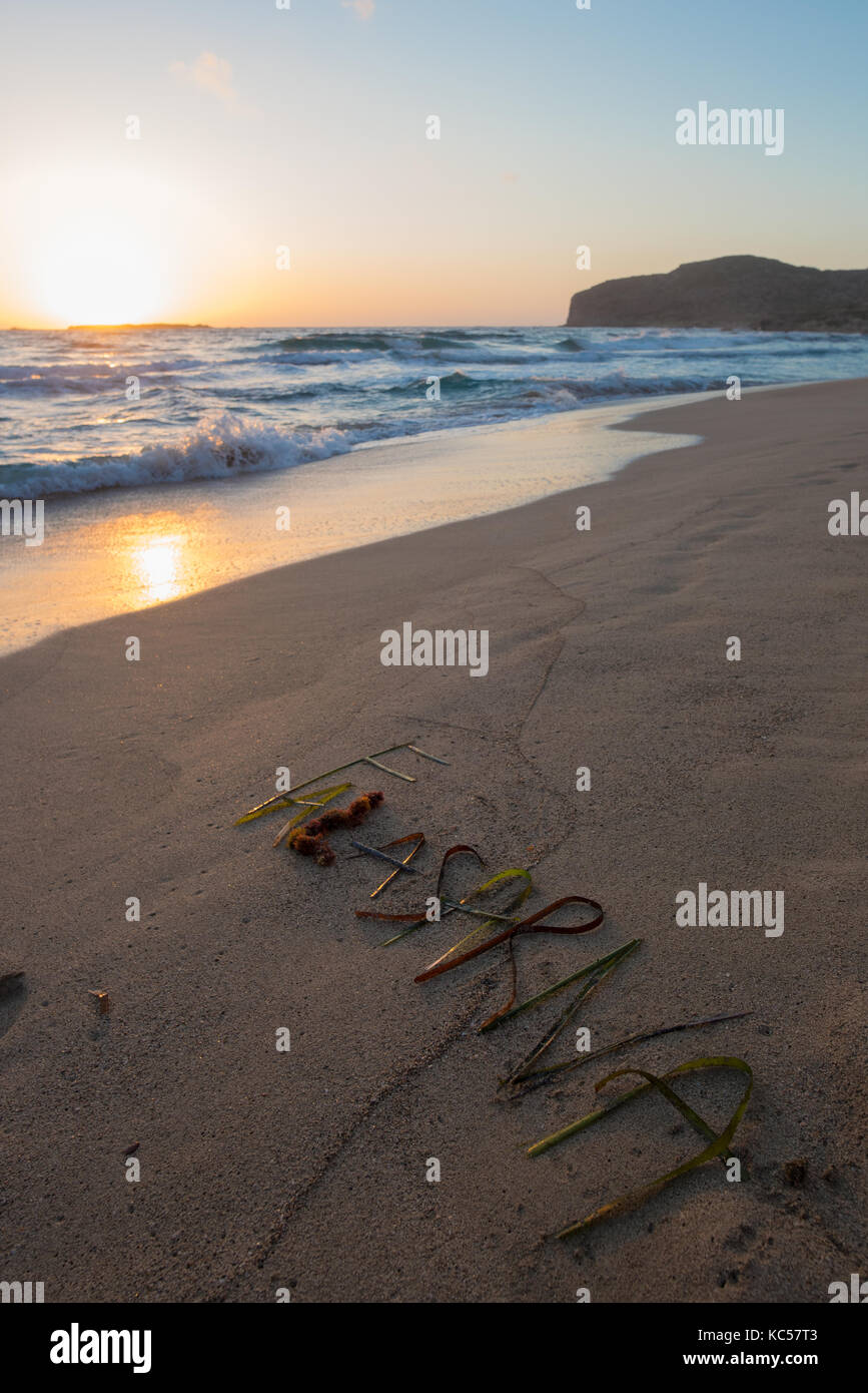 Sunset in Falassarna beach with inscription in sand made from seaweed ...