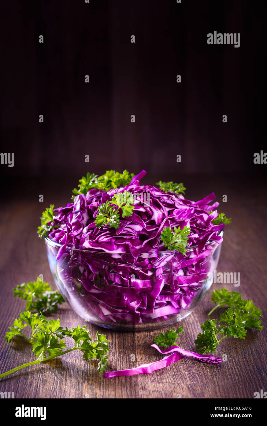 Shredded red cabbage in a glass bowl on natural dark rustic background ...