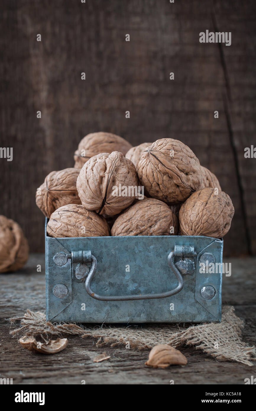 Walnuts in a small iron box and a canvas napkin. Wooden background ...