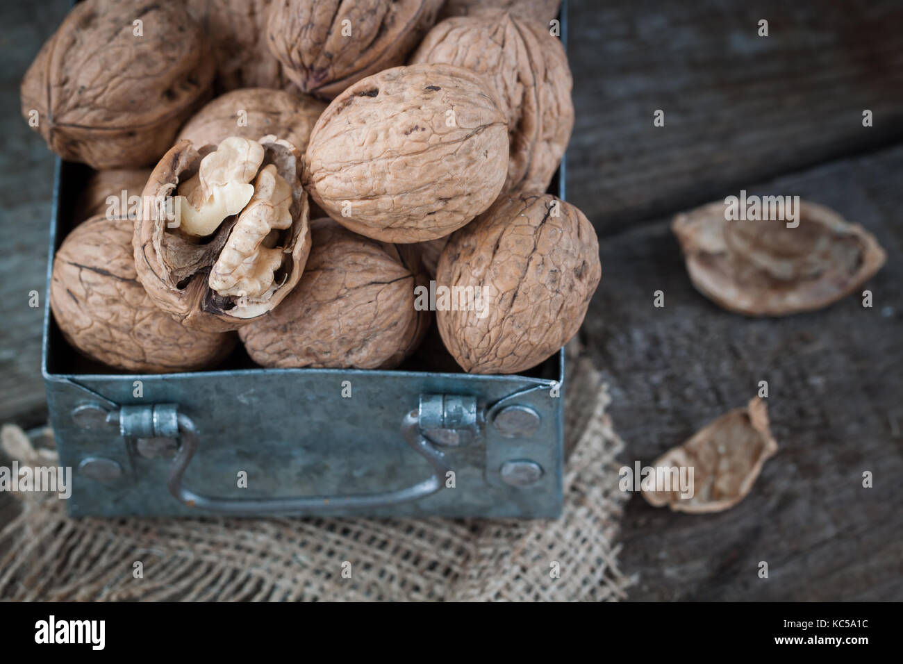 Walnuts in a small iron box and a canvas napkin. Wooden background ...