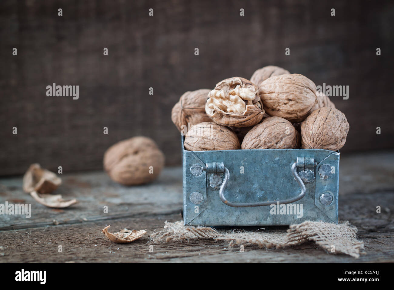 Walnuts in a small iron box and a canvas napkin. Wooden background ...
