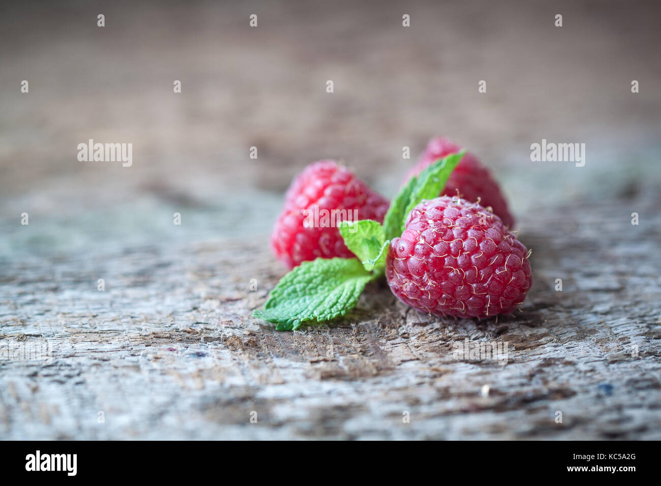 Raspberries with a mint leaf on the wooden background. Closeup Stock ...