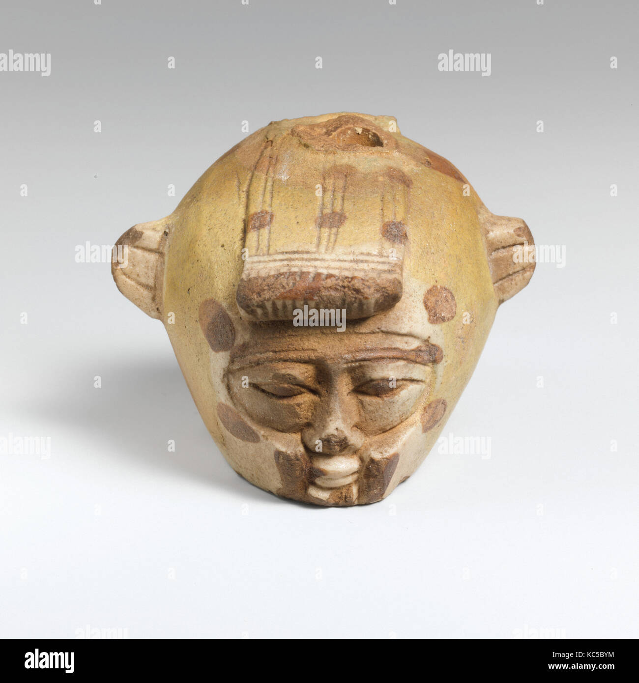 Faience aryballos (oil flask) in the form of a head wearing an animal ...