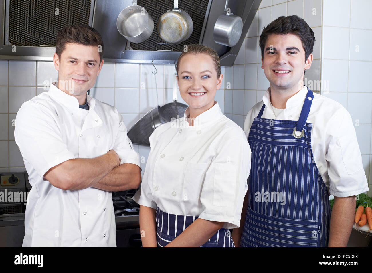 Portrait Of Chef And Staff Standing By Cooker In Kitchen Stock Photo ...
