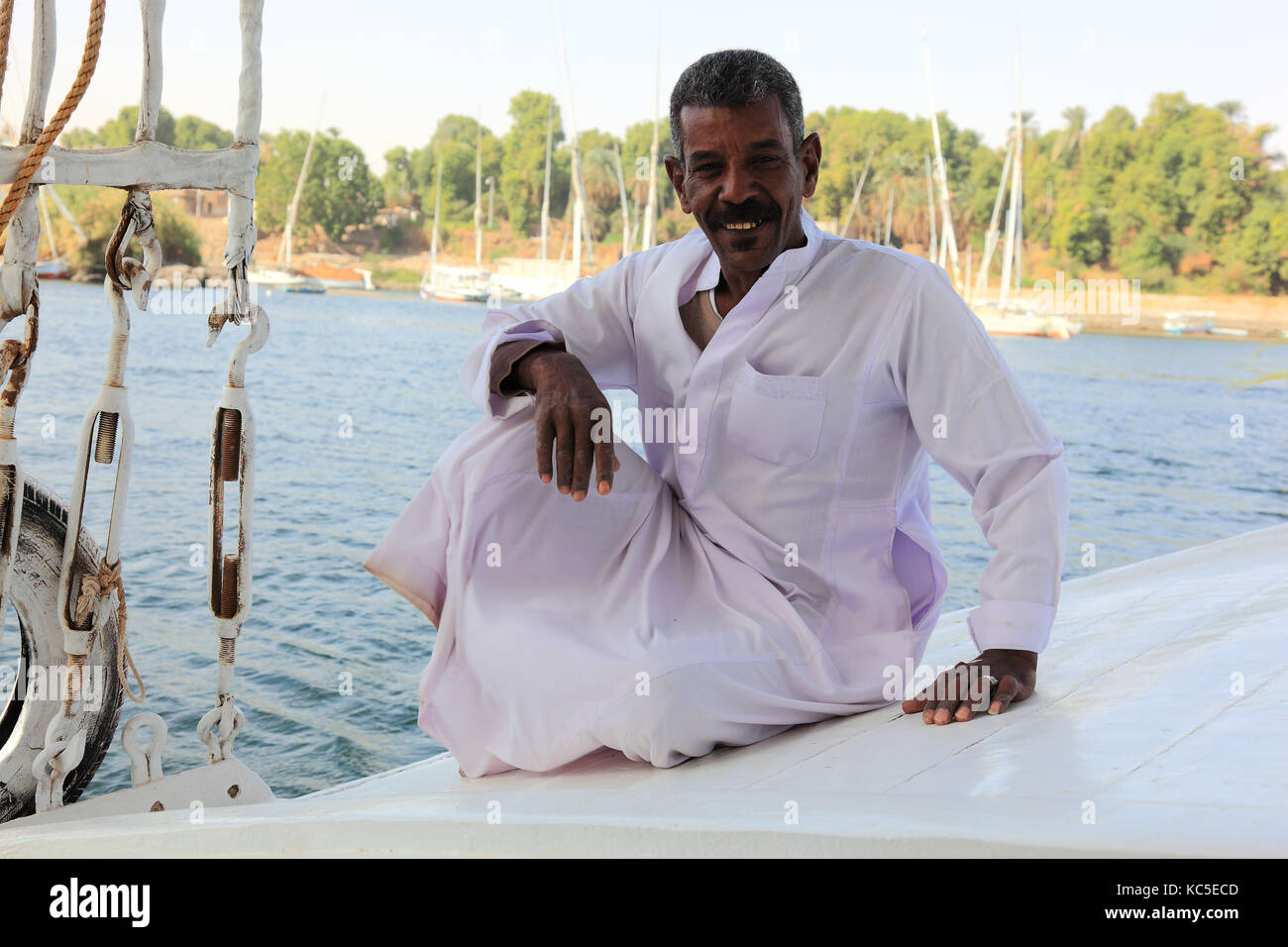 Arab man sitting on the deck of a sailing boat on the Nile near Aswan ...