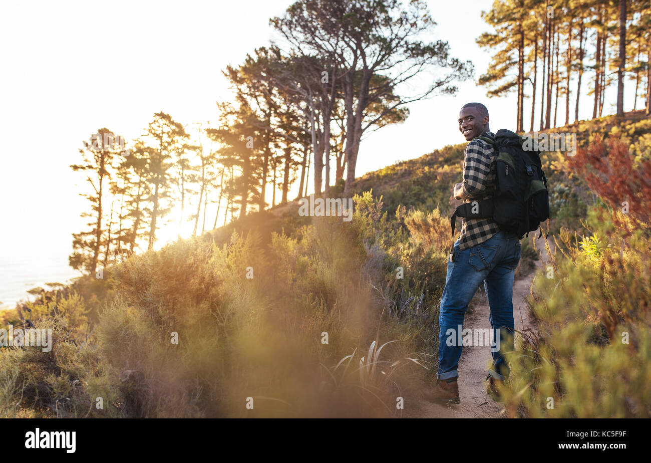 Smiling young African man hiking alone up a trail Stock Photo - Alamy