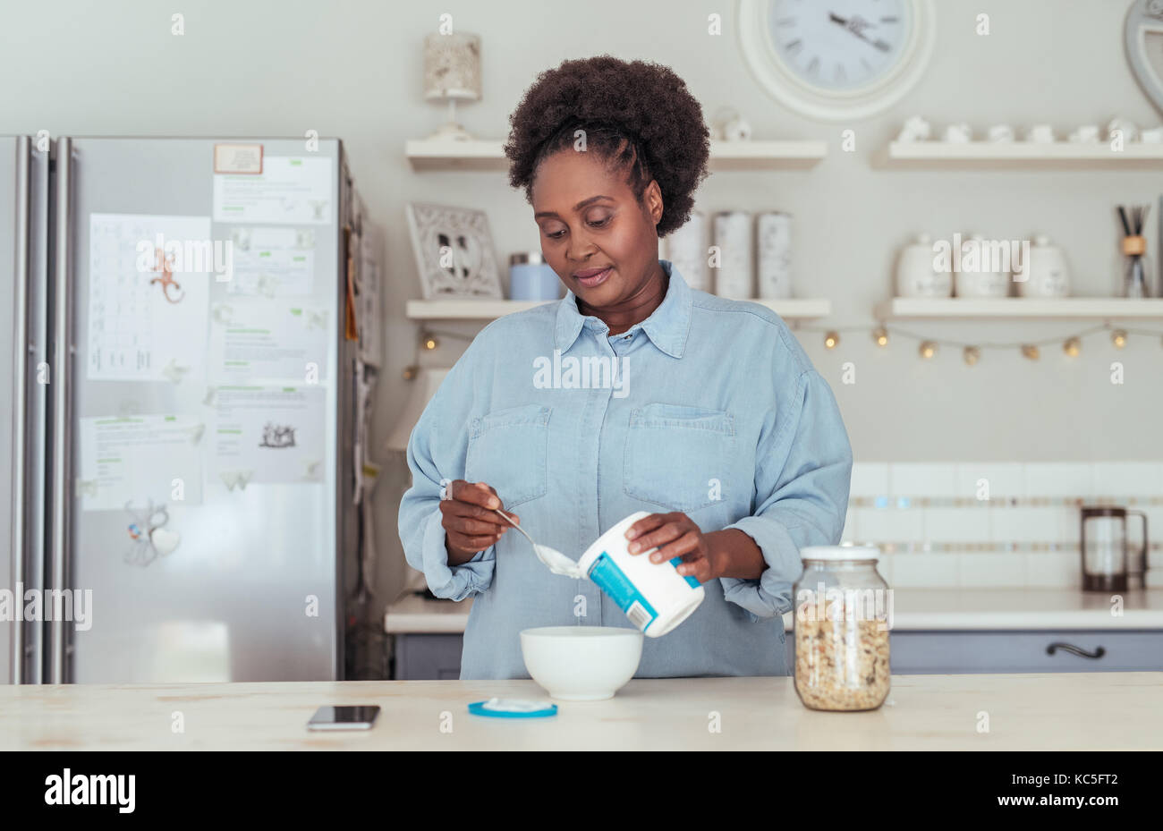 Young African woman having yoghurt with her cereal for breakfast Stock ...