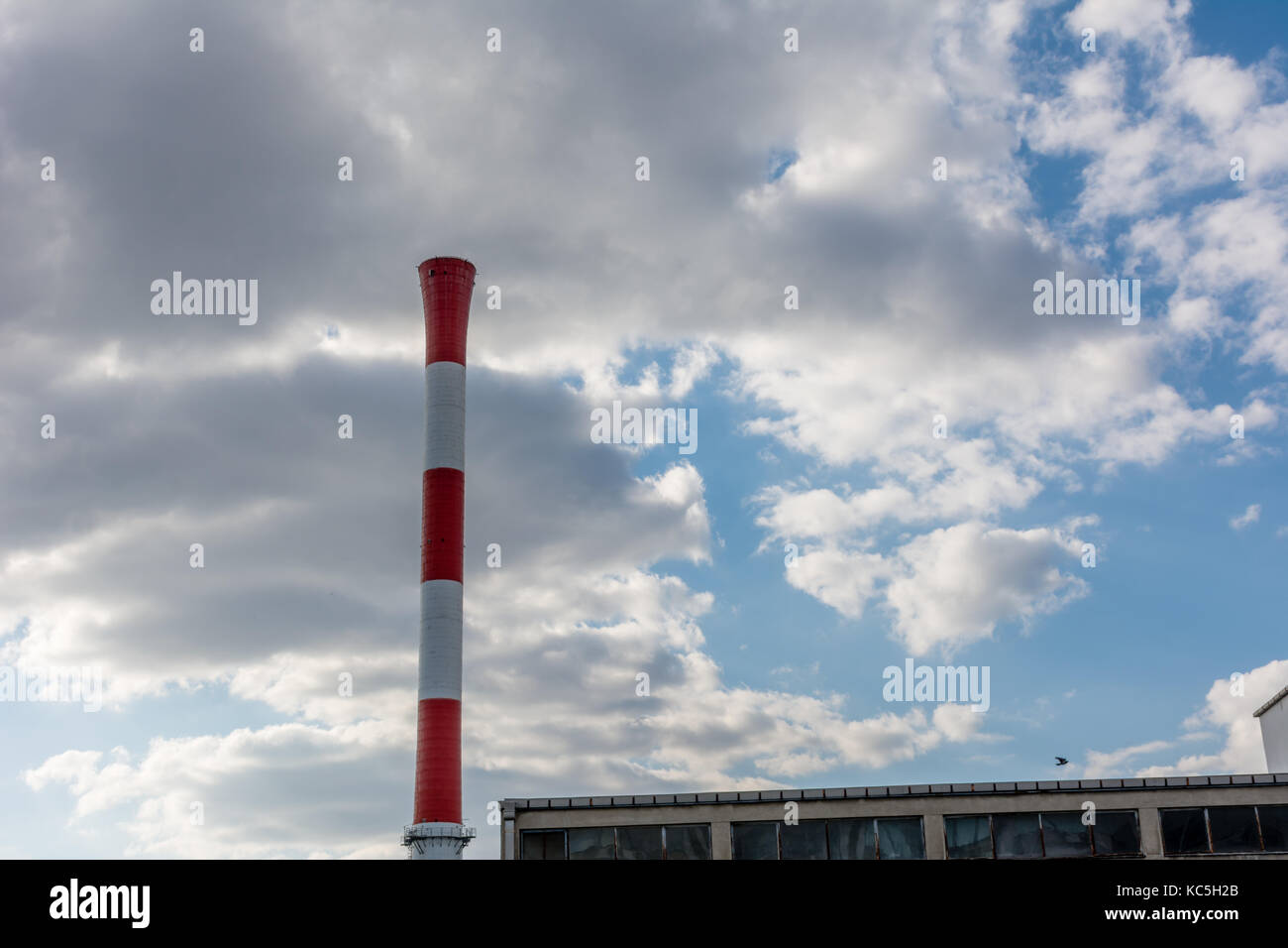 Factory chimney red white color on cloudy sky background left align ...