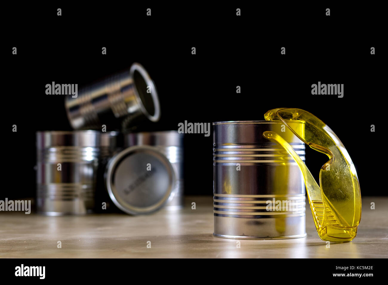 Paint tins set on a workshop table. Table with light wood, black ...