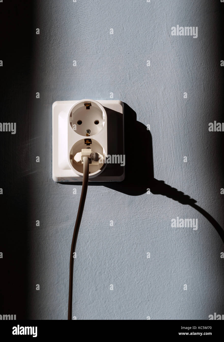 Electrical plug socket with electric cable inserted into one of the ...