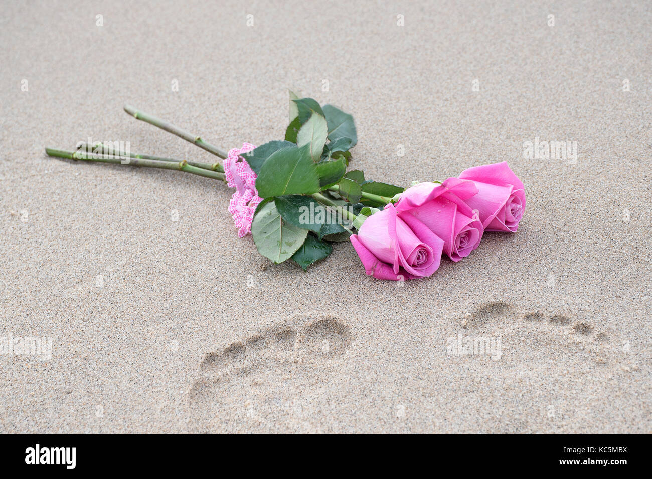 pink rose bouquet on beach sand with footprints Stock Photo - Alamy