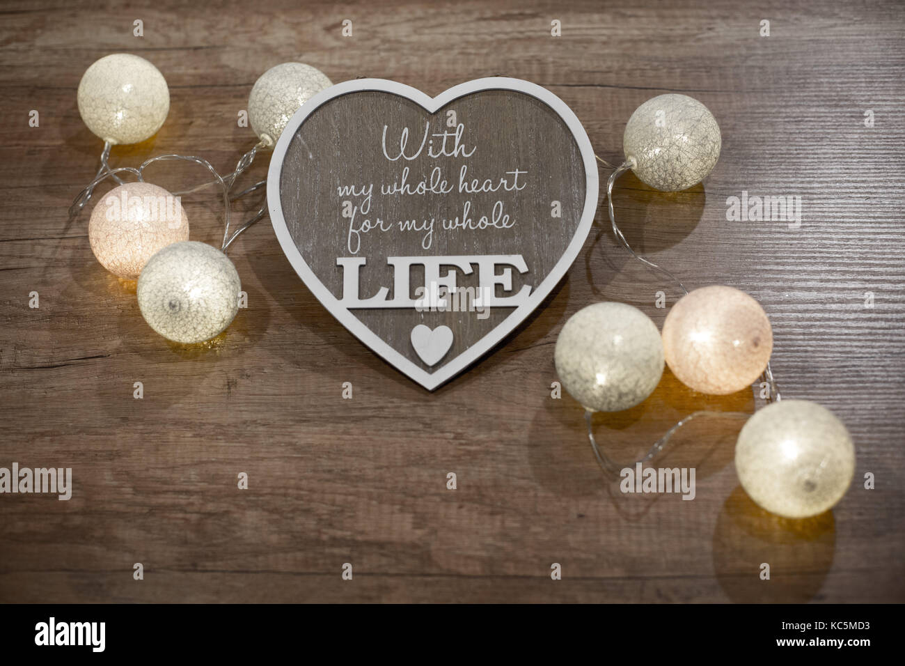 Decorative heart with text and multicolour lights on the wooden table ...