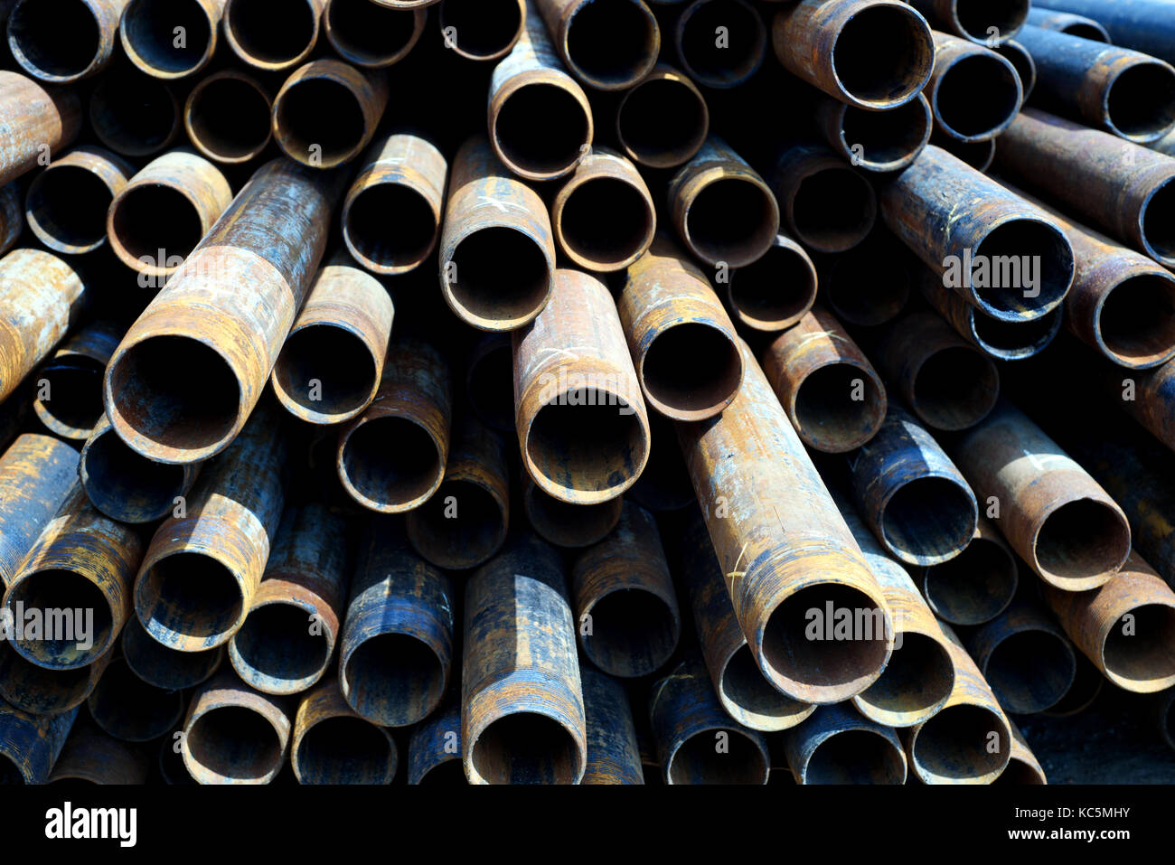 Metal tubes and pipes stacked in a pile of different lengths creates ...