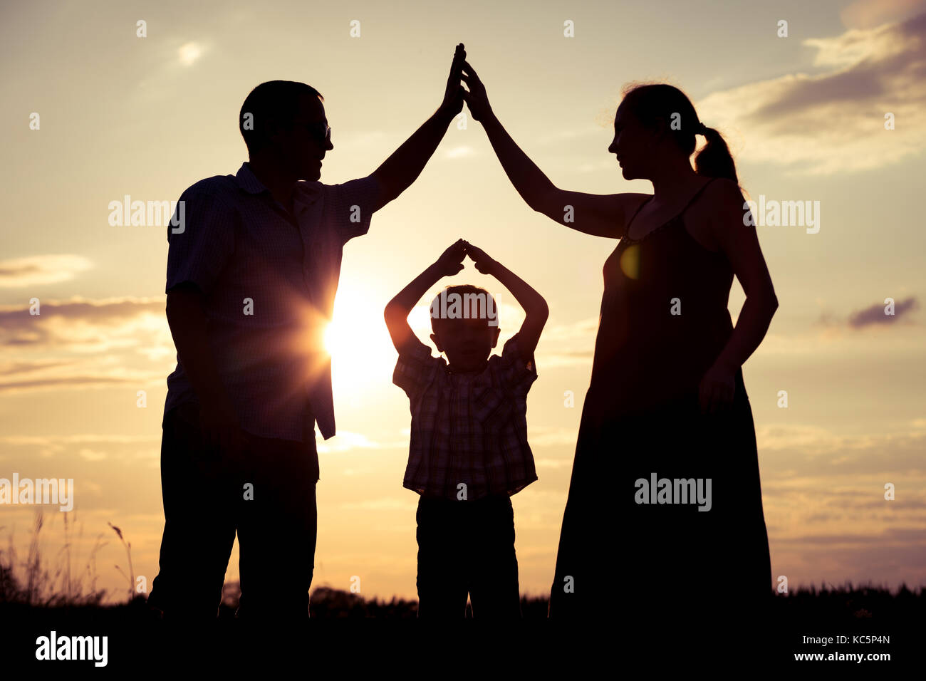 Happy family standing in the park at the sunset time. People having fun ...