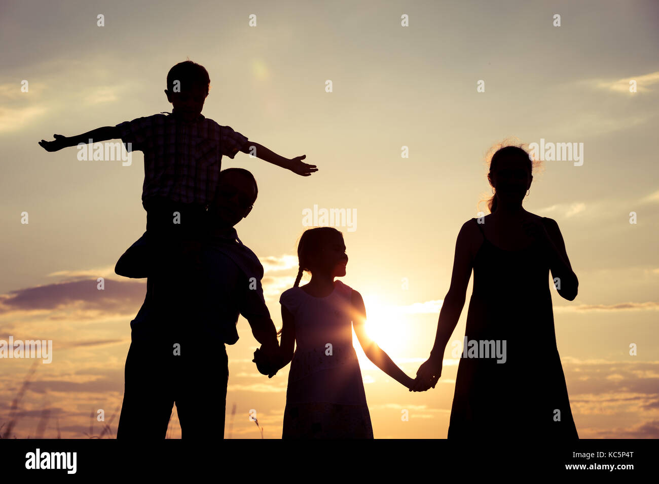 Happy family standing in the park at the sunset time. People having fun ...