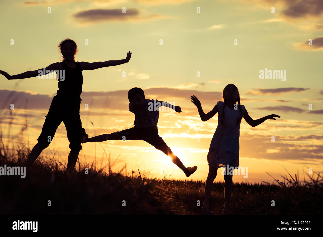 Happy children playing in the park at the sunset time. People having ...