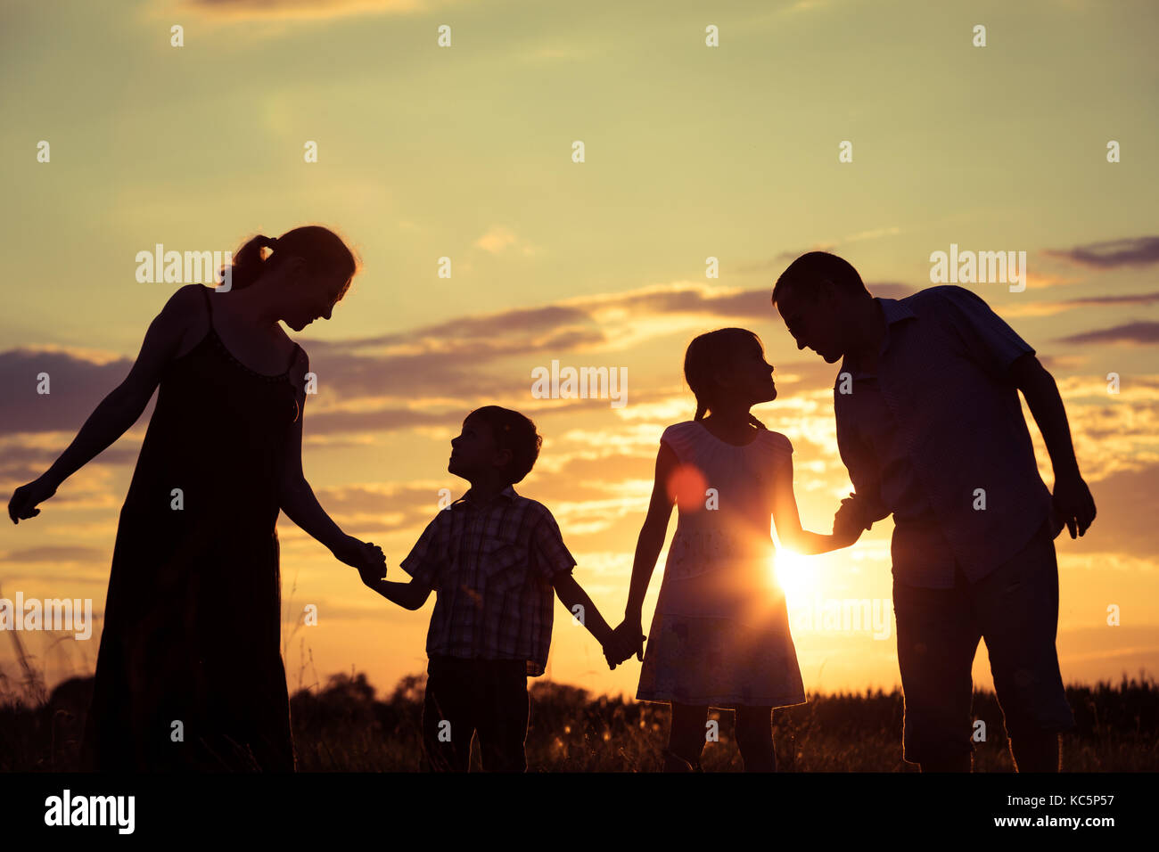 Happy family standing in the park at the sunset time. People having fun ...