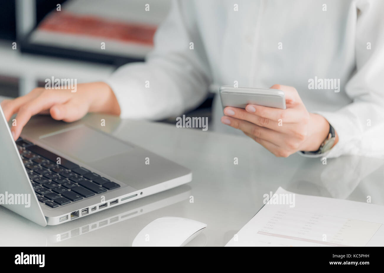 Close up businesswoman holding mobile phone and using laptop computer ...
