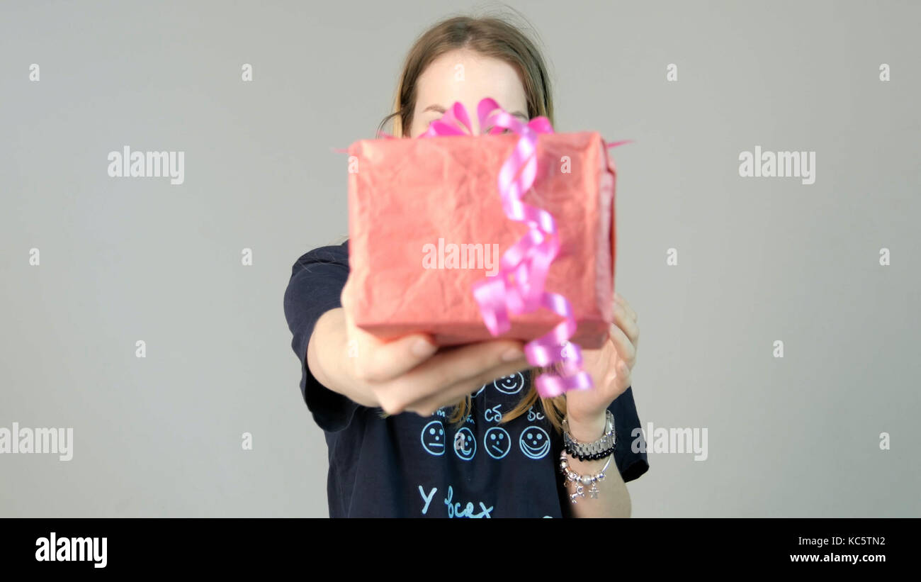 Young woman giving a gift on a white background. Young woman giving a ...
