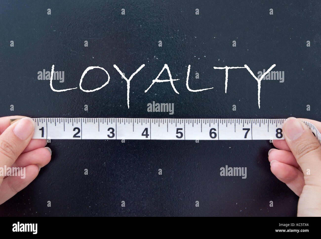 Hands measuring loyalty on a chalkboard Stock Photo - Alamy