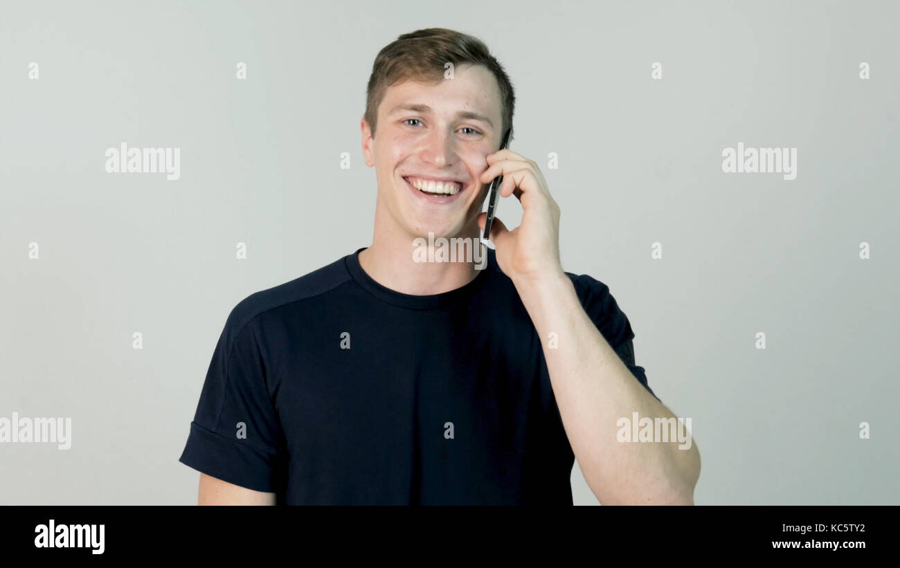 Happy smiling young man talking on mobile isolated on white background ...