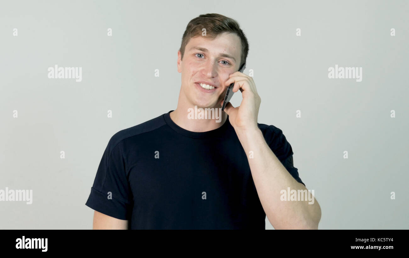 Happy smiling young man talking on mobile isolated on white background ...