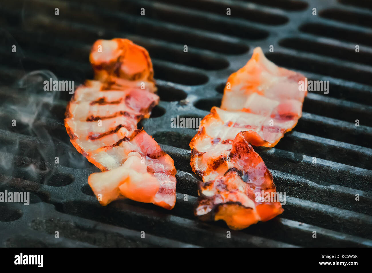 Grilled bacon skewers on a black background. Delicious strips of fatty ...