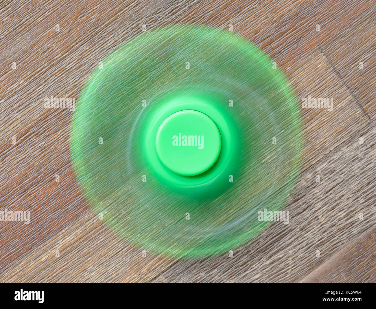 Image of Fidget finger spinner stress toy - Green spinner on a wooden ...