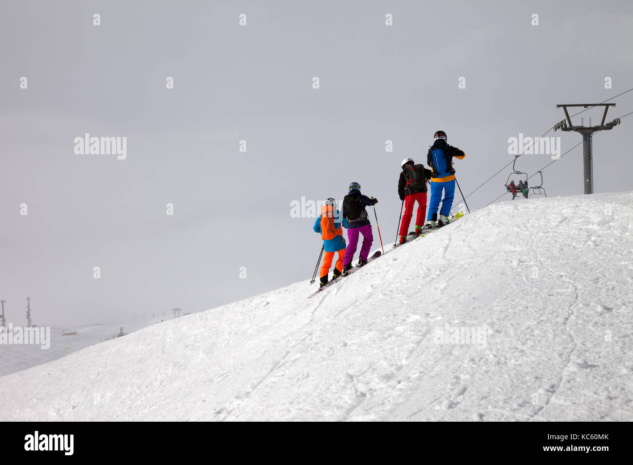 Skiers before downhill on off-piste slope and overcast misty sky at day ...