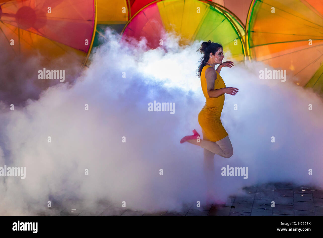 Street festival performer dancing through dry ice in front of a ...