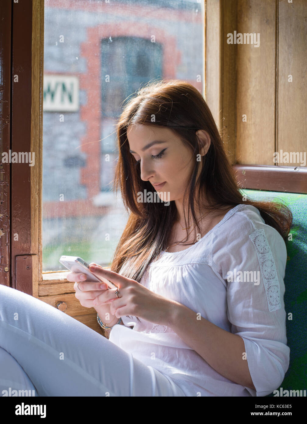 Pretty young lady on an old train using her cellphone Stock Photo - Alamy