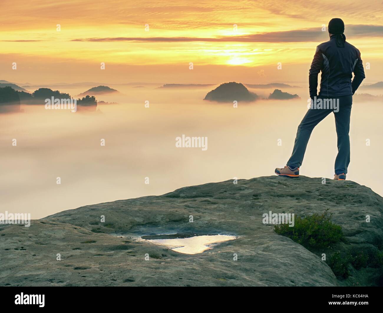 Man stands alone on the peak of rock. Hiker watching to autumn Sun at ...