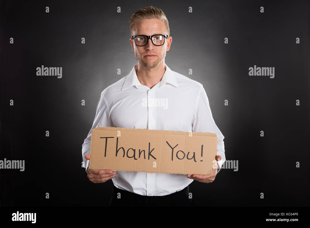 Man Holding Cardboard With Thank You Text Written On It Against Black ...