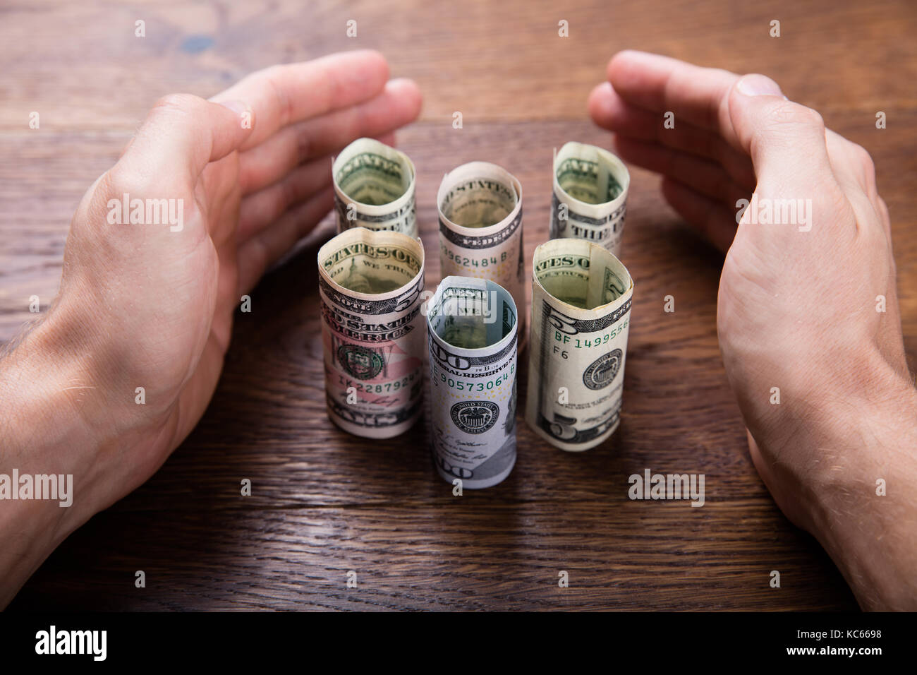 Close-up Of Hands Protecting The Rolled Up Currency Notes On Table ...