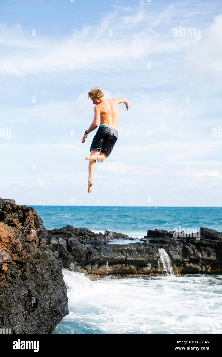Young man jumping into sea Stock Photo - Alamy