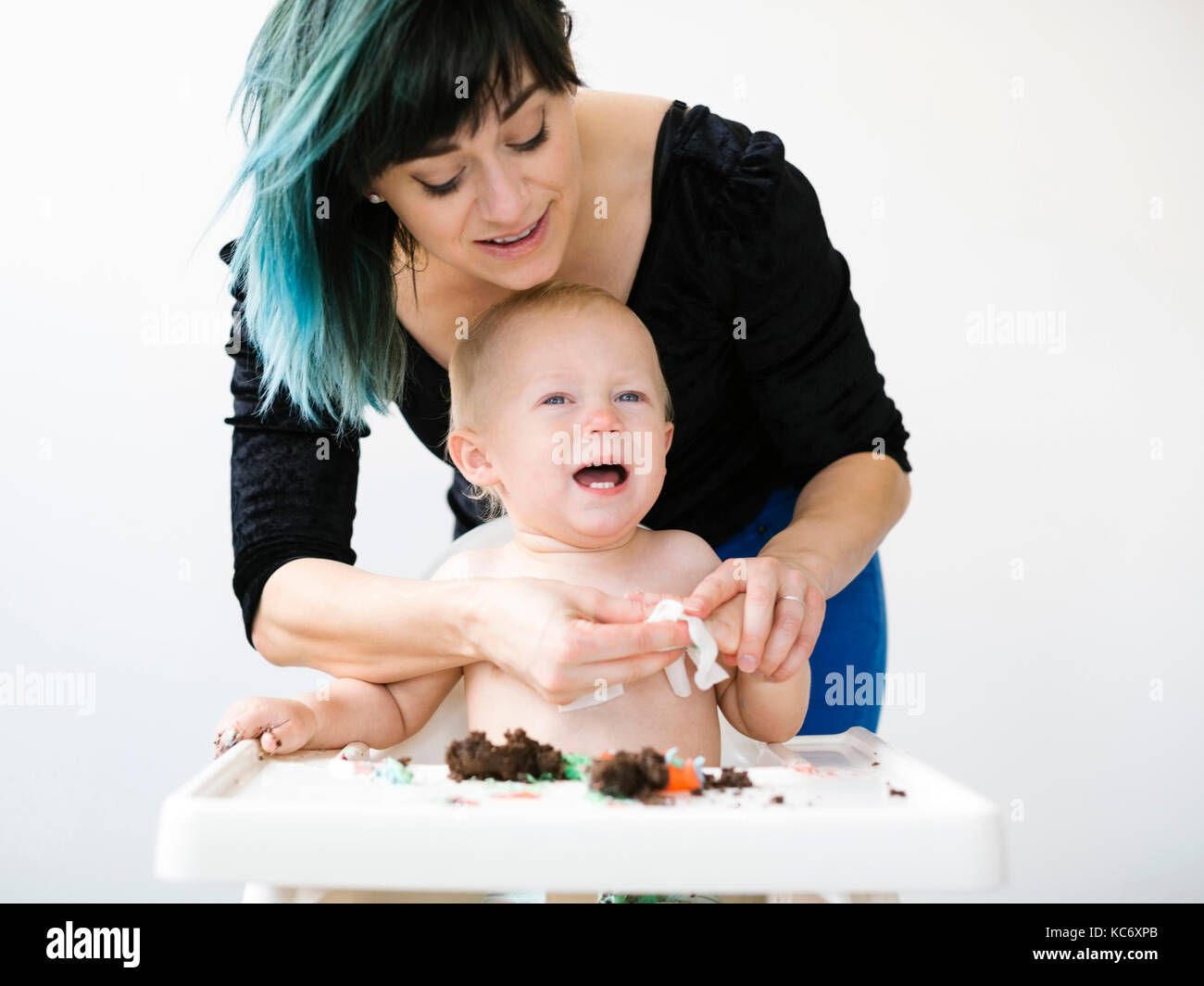 Mother cleaning baby boy (12-17 months) from cupcake Stock Photo - Alamy