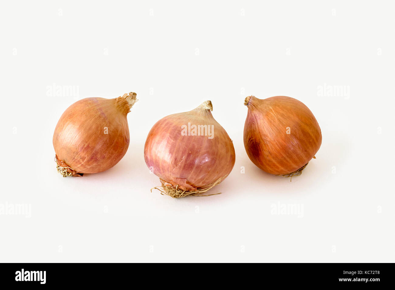Three whole ripe onions on a white background Stock Photo - Alamy