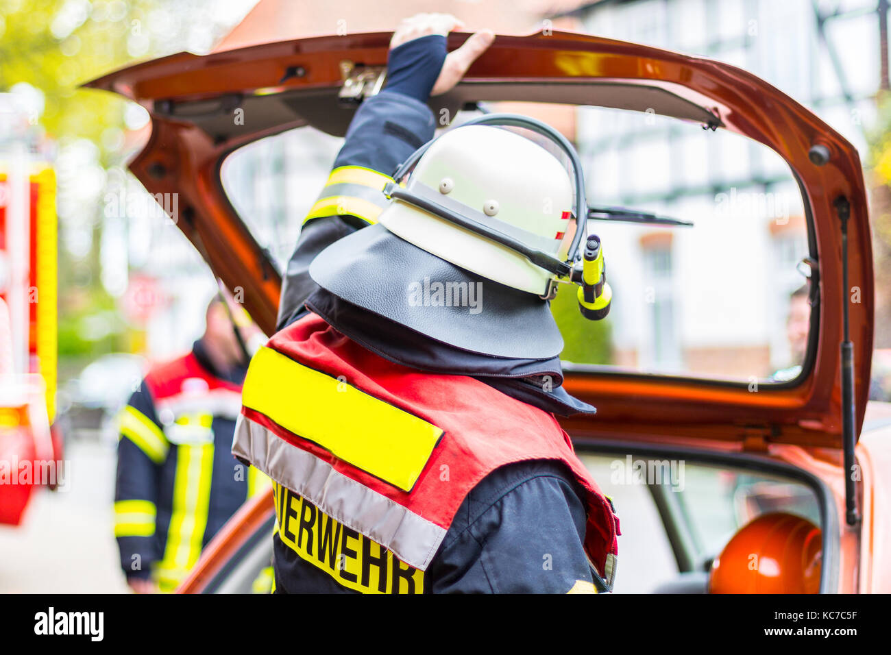 german fireman with helmet holds his hand on car bootlid Stock Photo ...