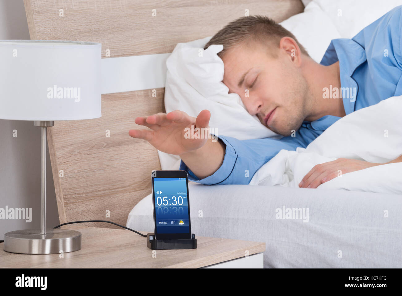Man Lying On Bed Snoozing Alarm On Mobile Phone Screen Stock Photo - Alamy