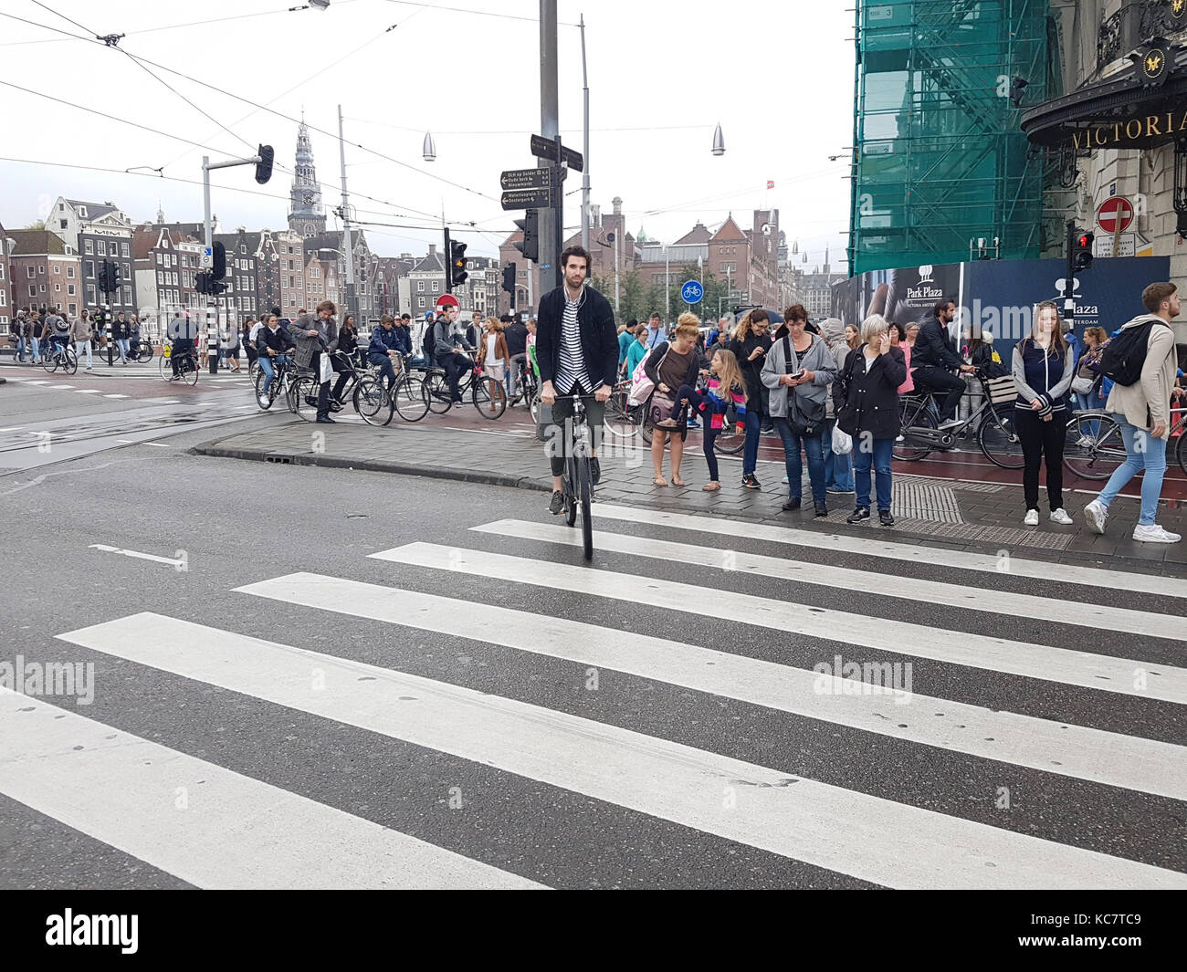 Crowd waits on city intersection on Damrak for lights to change while a ...