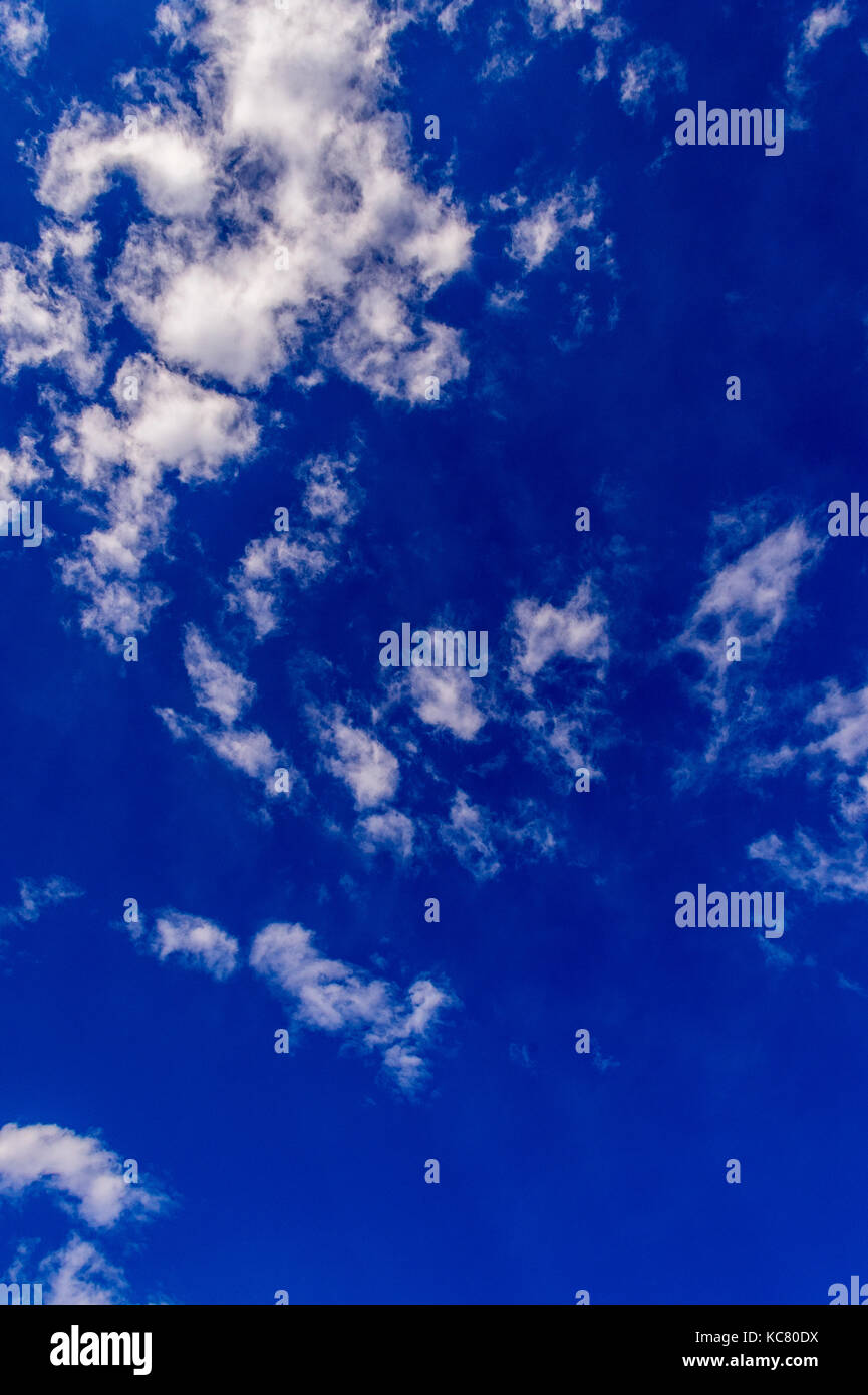 Deep blue sky with scattered clouds Stock Photo - Alamy