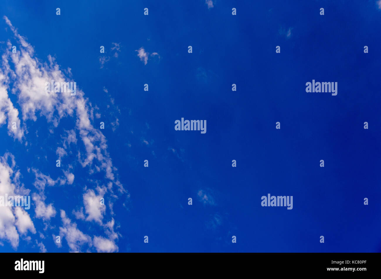 Deep blue sky with scattered clouds Stock Photo - Alamy
