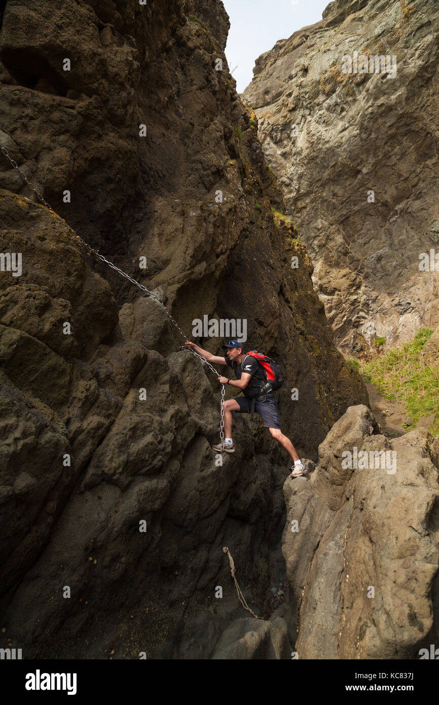 A walker stepping across a gap on the chain walk Elie, Fife, Scotland ...