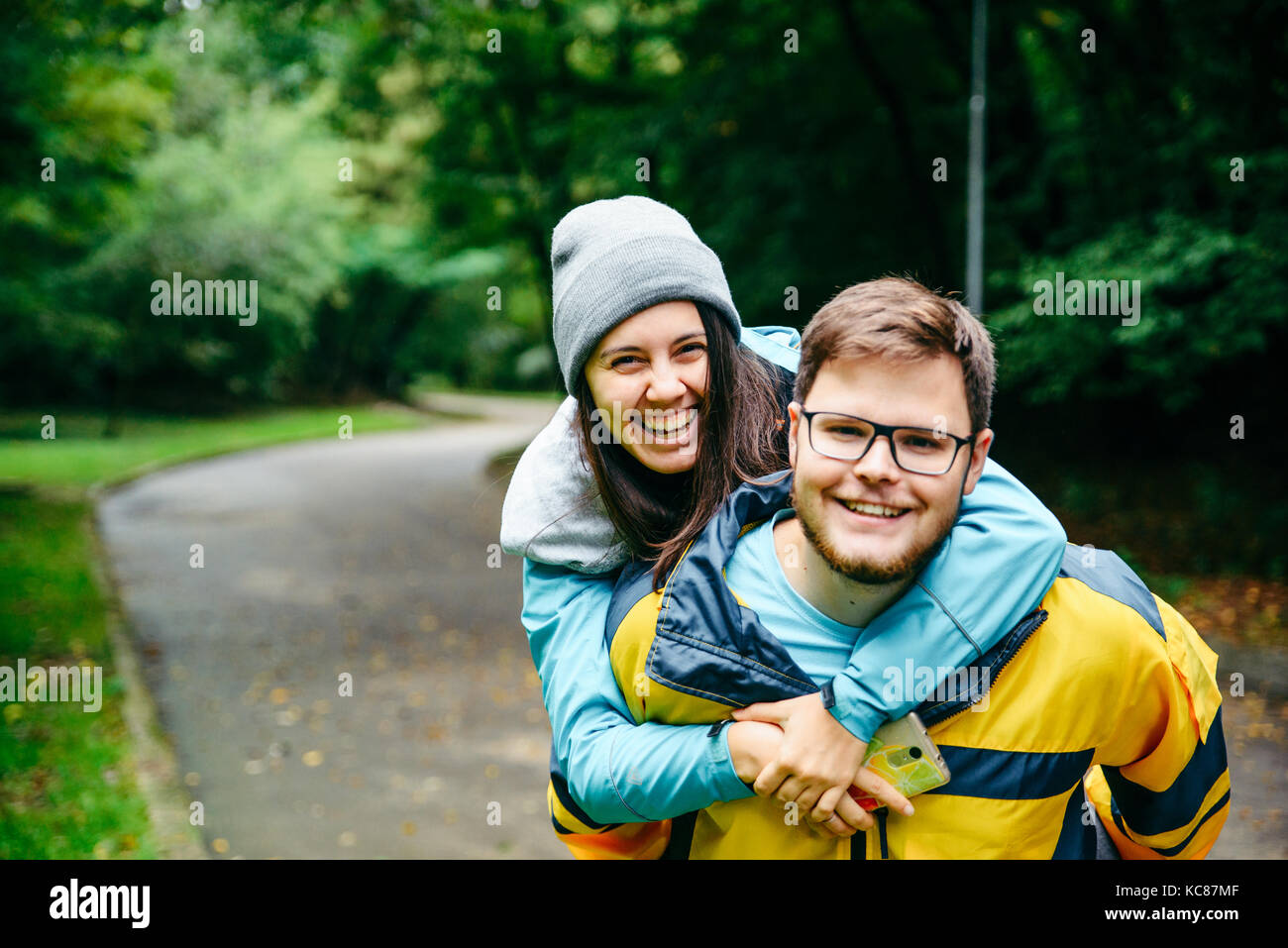 laughing couple in sport wear, woman jump on man shoulders piggyback ...