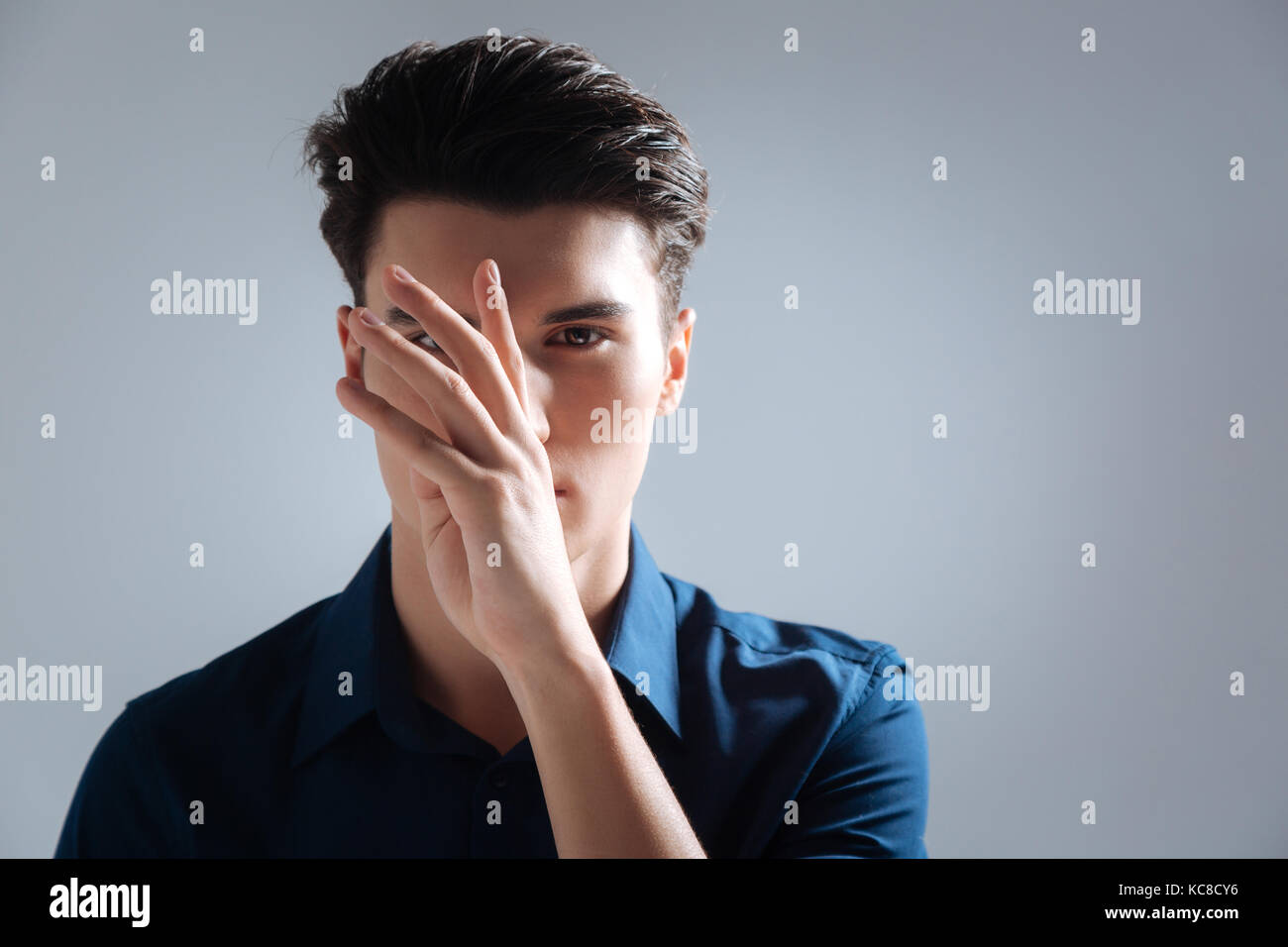 Playful brunette holding arm in front of his nose Stock Photo - Alamy