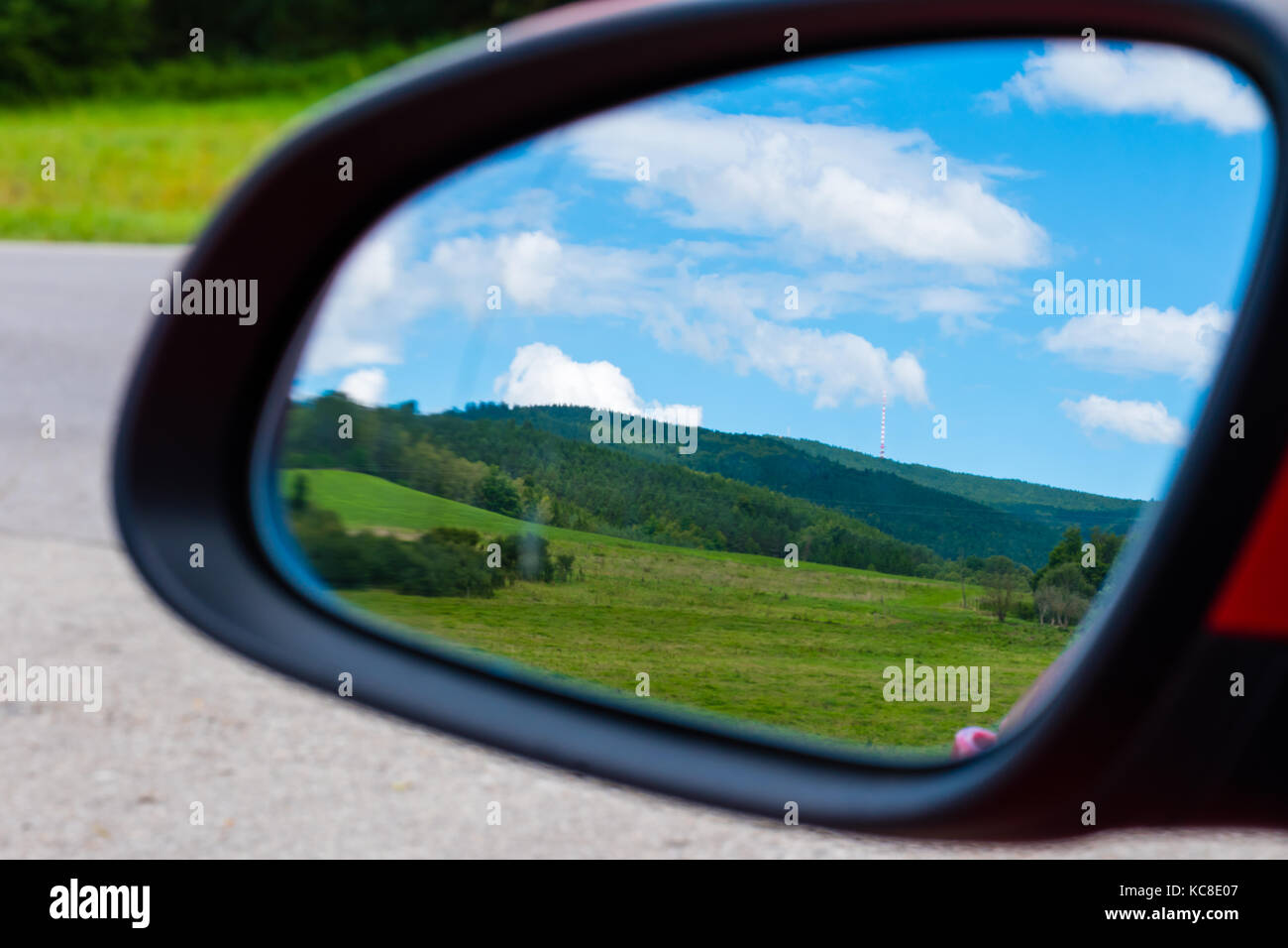 The view to the beautiful land through mirror of car. Nice summer blue ...