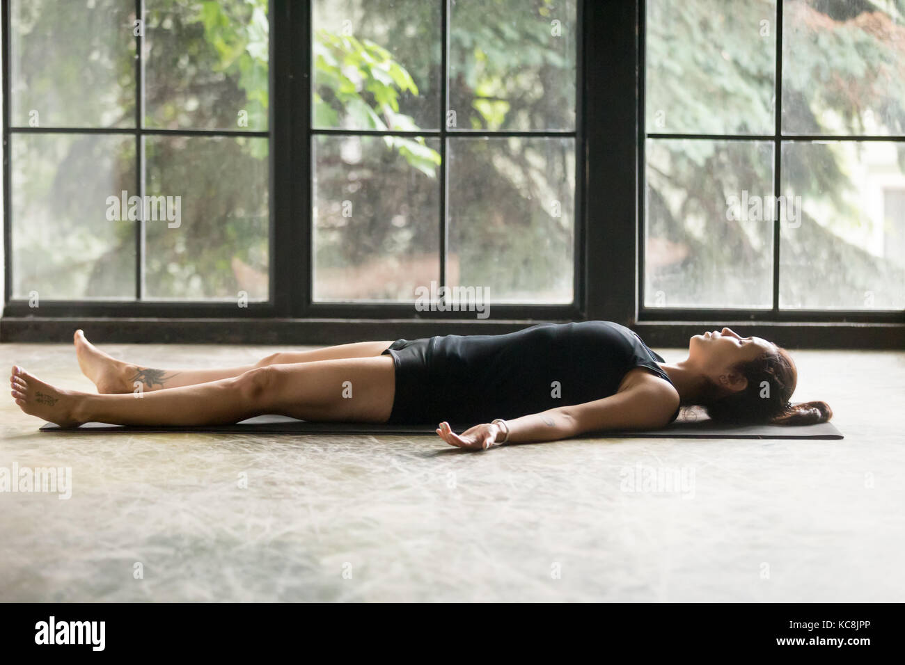 Young attractive woman in Corpse pose, studio background Stock Photo ...